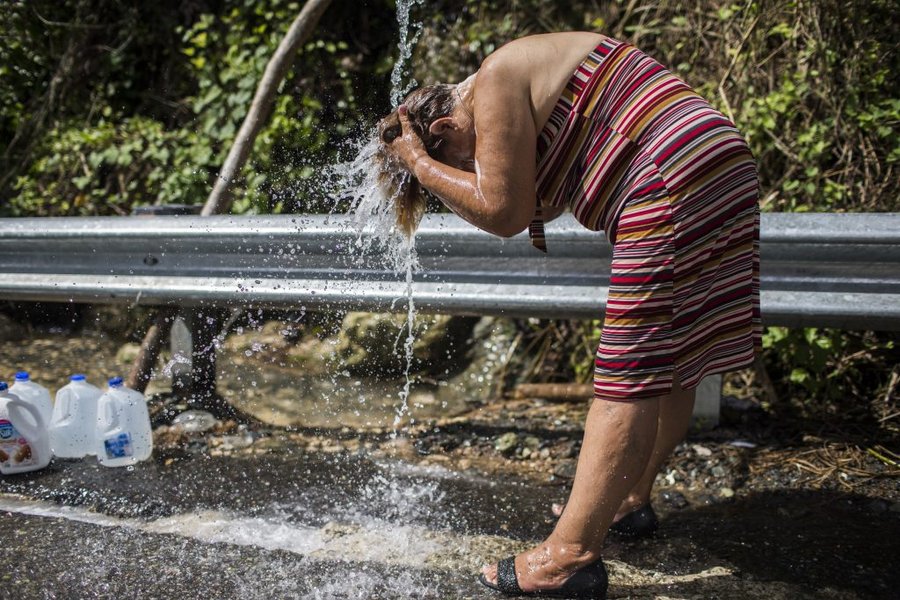 Carmen Rodriguez showers using water sent down from higher elevations ...